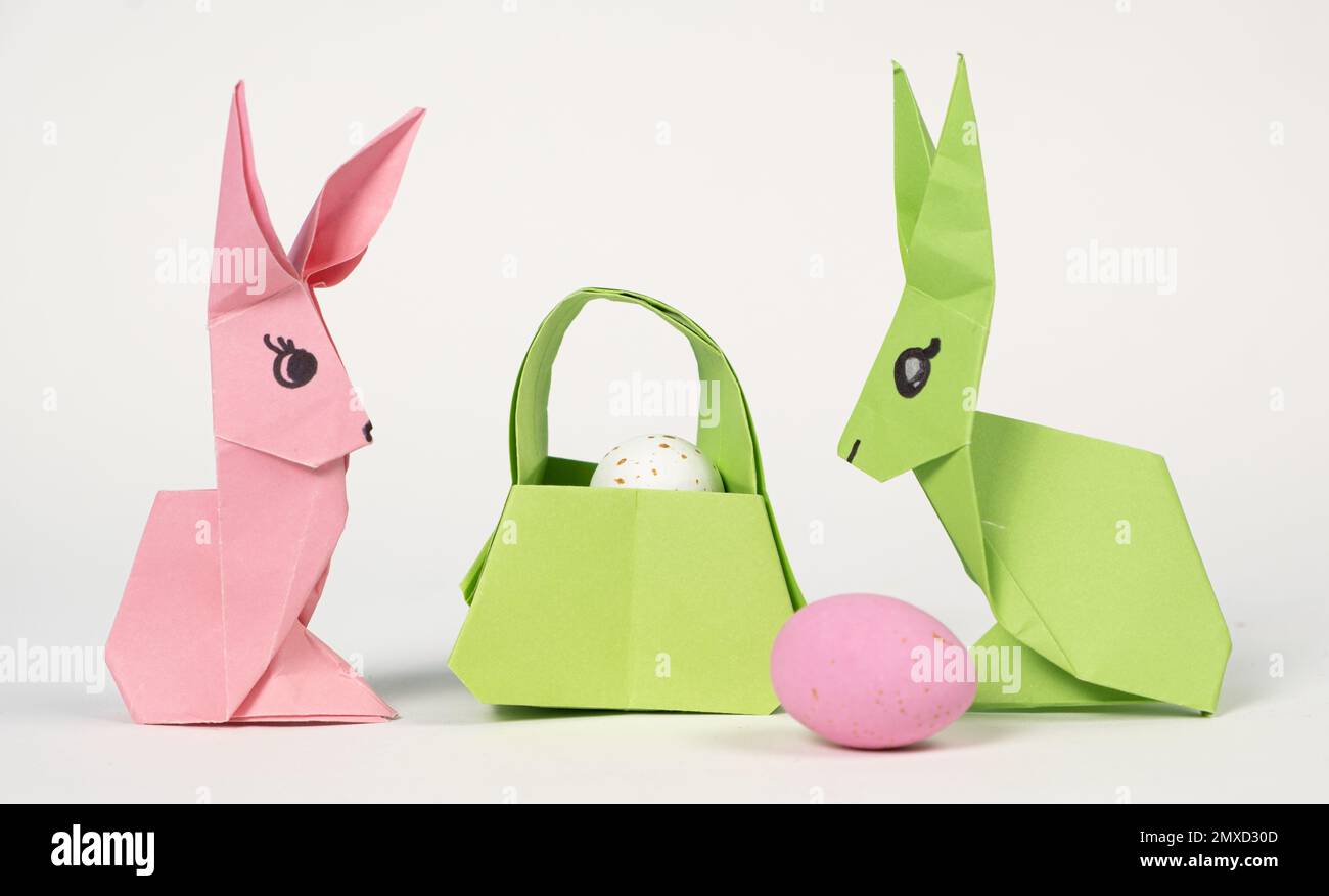 Easter origami bunnies and a basket of eggs on a white background ...