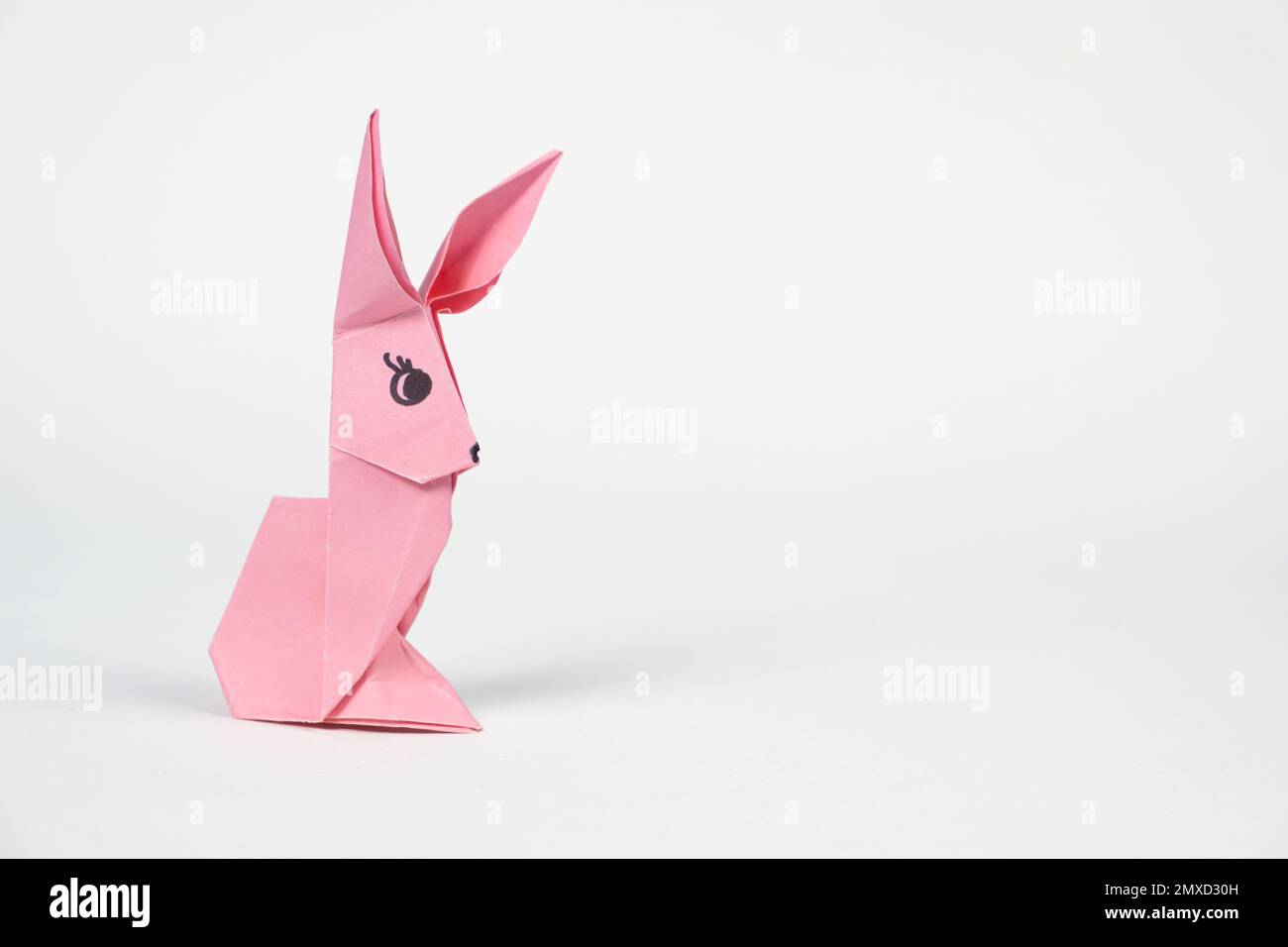 A pink origami rabbit on a white background. Crafts for Easter, fold ...