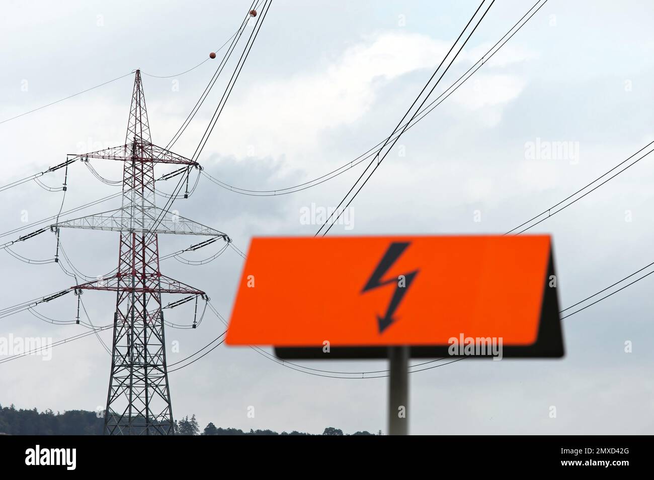 high-voltage transmission pole with power lines, sign 'Caution Heavy ...