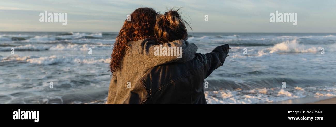 Back view of woman hugging friend on beach in Barcelona, banner Stock ...