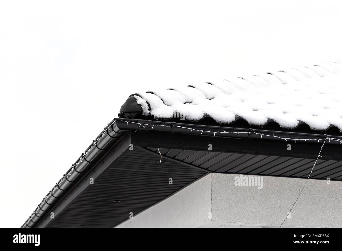 The roof of a single-family house is covered with snow against a cloudy ...