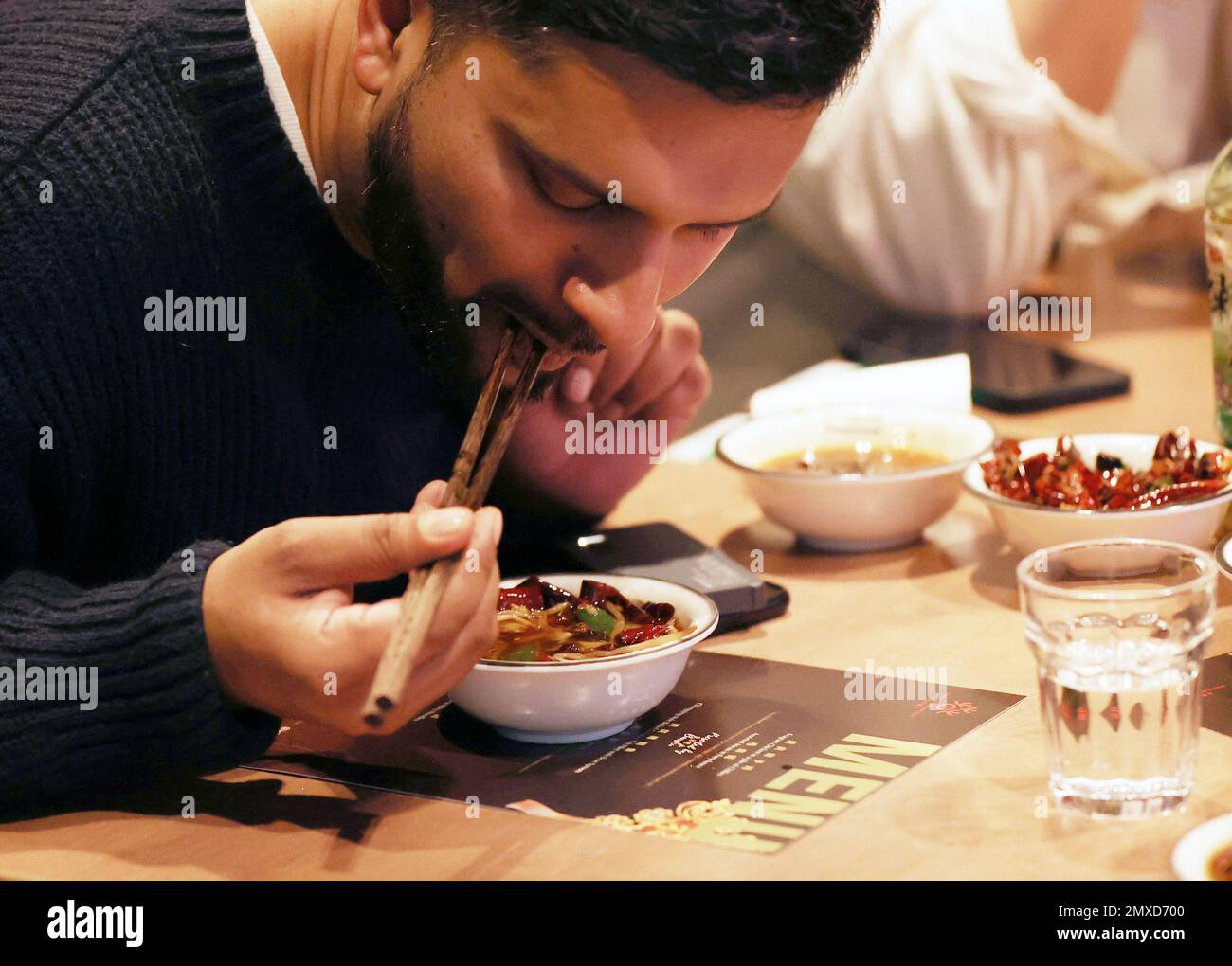 London, Britain. 2nd Feb, 2023. A man tastes boiled spicy fish fillet ...