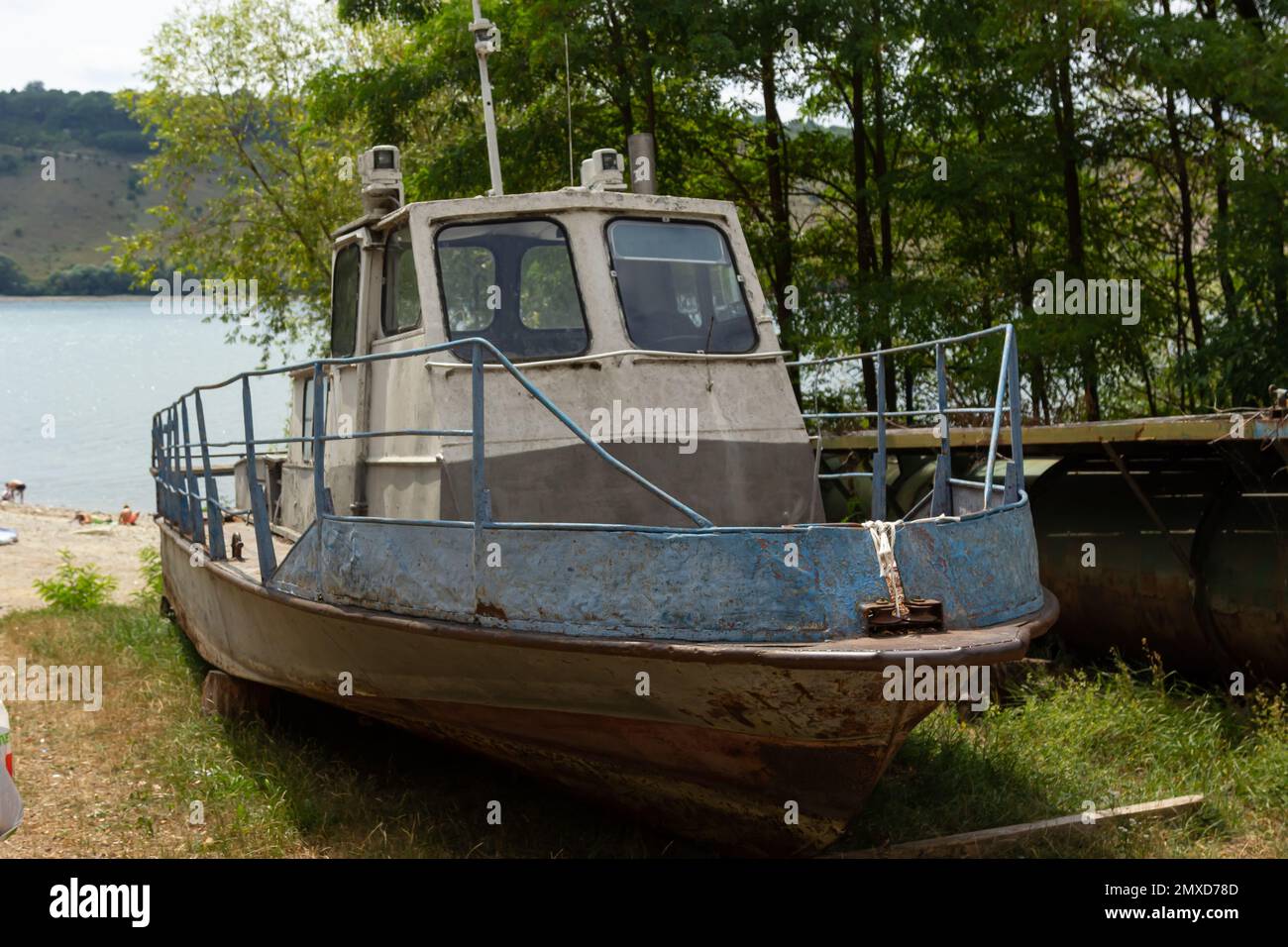 Old abandoned boat, ship on the shore against the background of trees ...