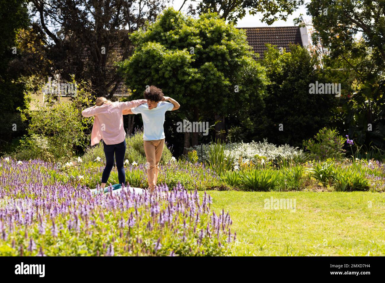 Happy diverse couple having fun, dancing in sunny garden, copy space ...