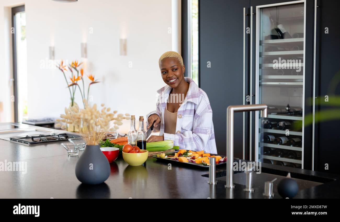 Happy african american woman cooking in kitchen, chopping vegetables ...