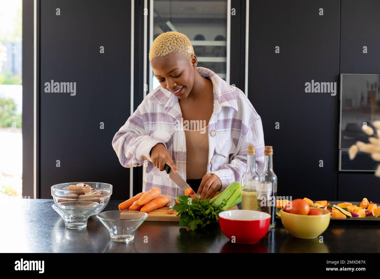 Happy african american woman cooking in kitchen, chopping vegetables ...