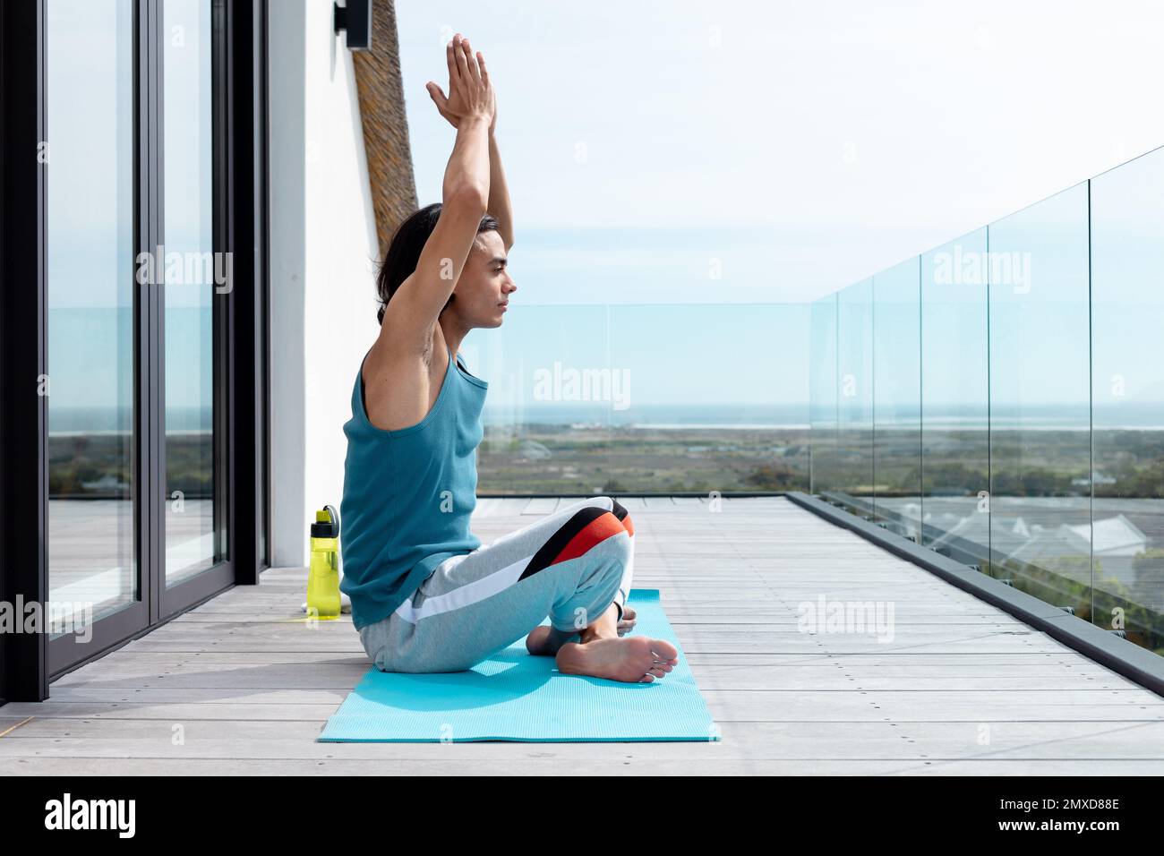 Happy biracial man doing yoga, meditating on balcony Stock Photo - Alamy