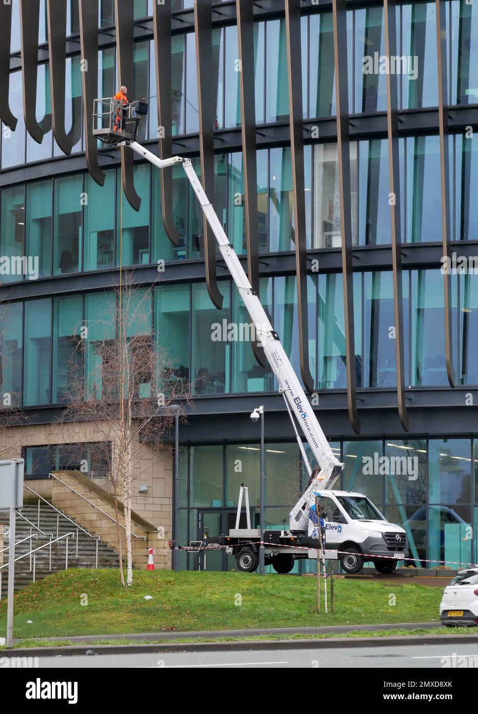Window cleaning a tall glass fronted building from a white arm on a ...