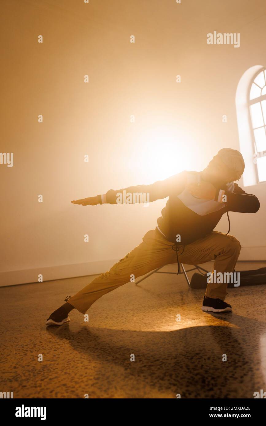 Vertical image of biracial male hip hop dancer dancing in smoked ...