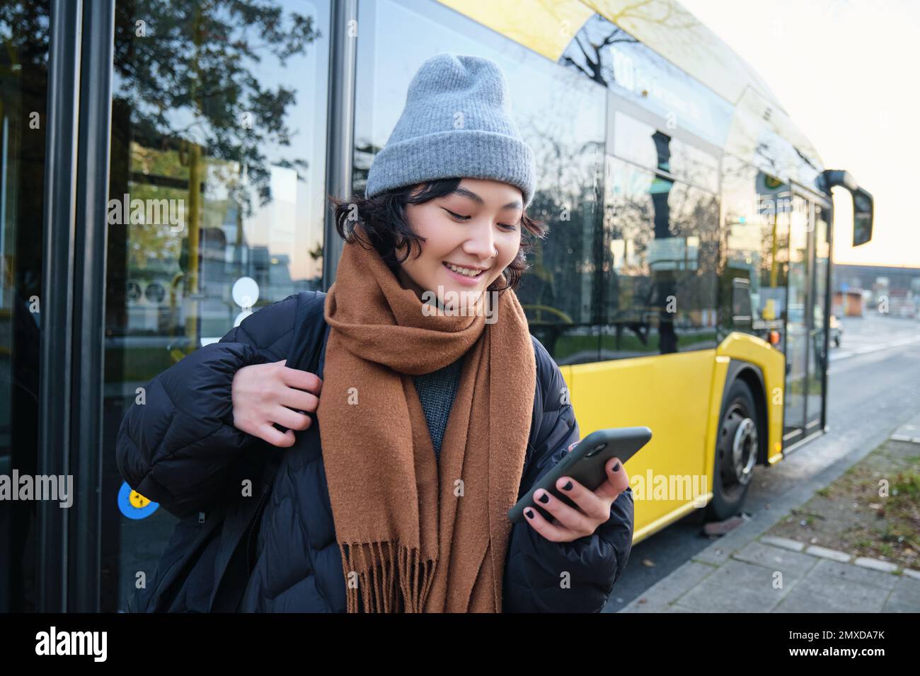 Image of girl student waiting for public transport, checks schedule on ...