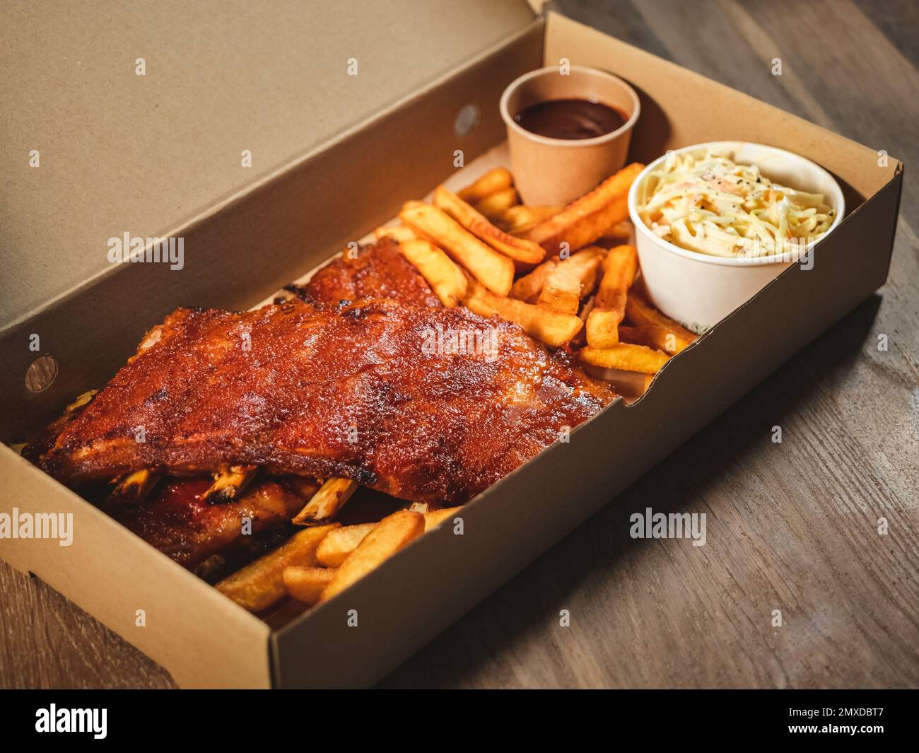 grilled pork ribs with french fries and sauces in a box for take away ...