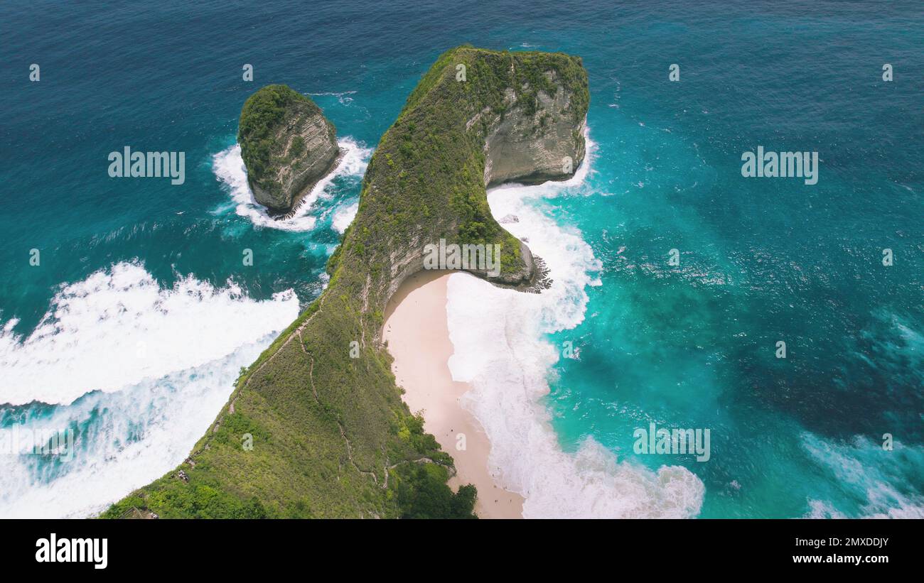 Kelingking sandy beach with tall overgrown rocky cliff and turquoise ...