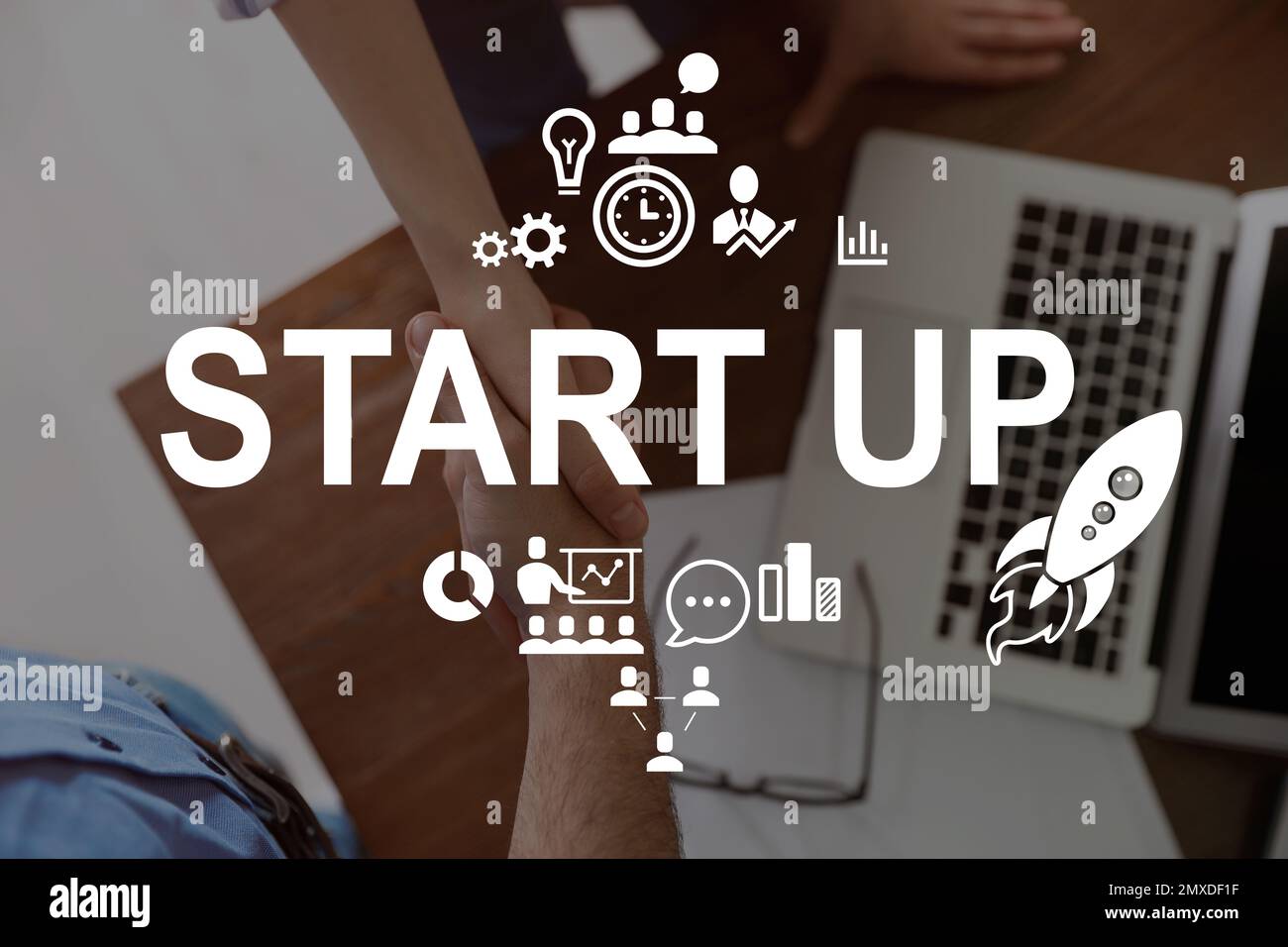 Business partners shaking hands and illustrated icons over table, top ...