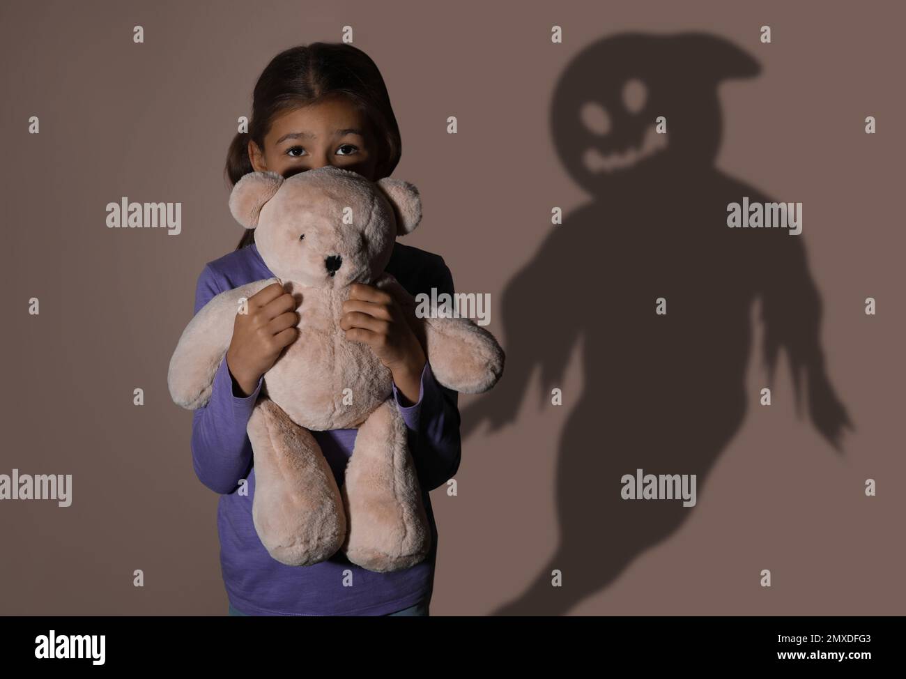 Scared little girl with teddy bear suffering from sciophobia and ...