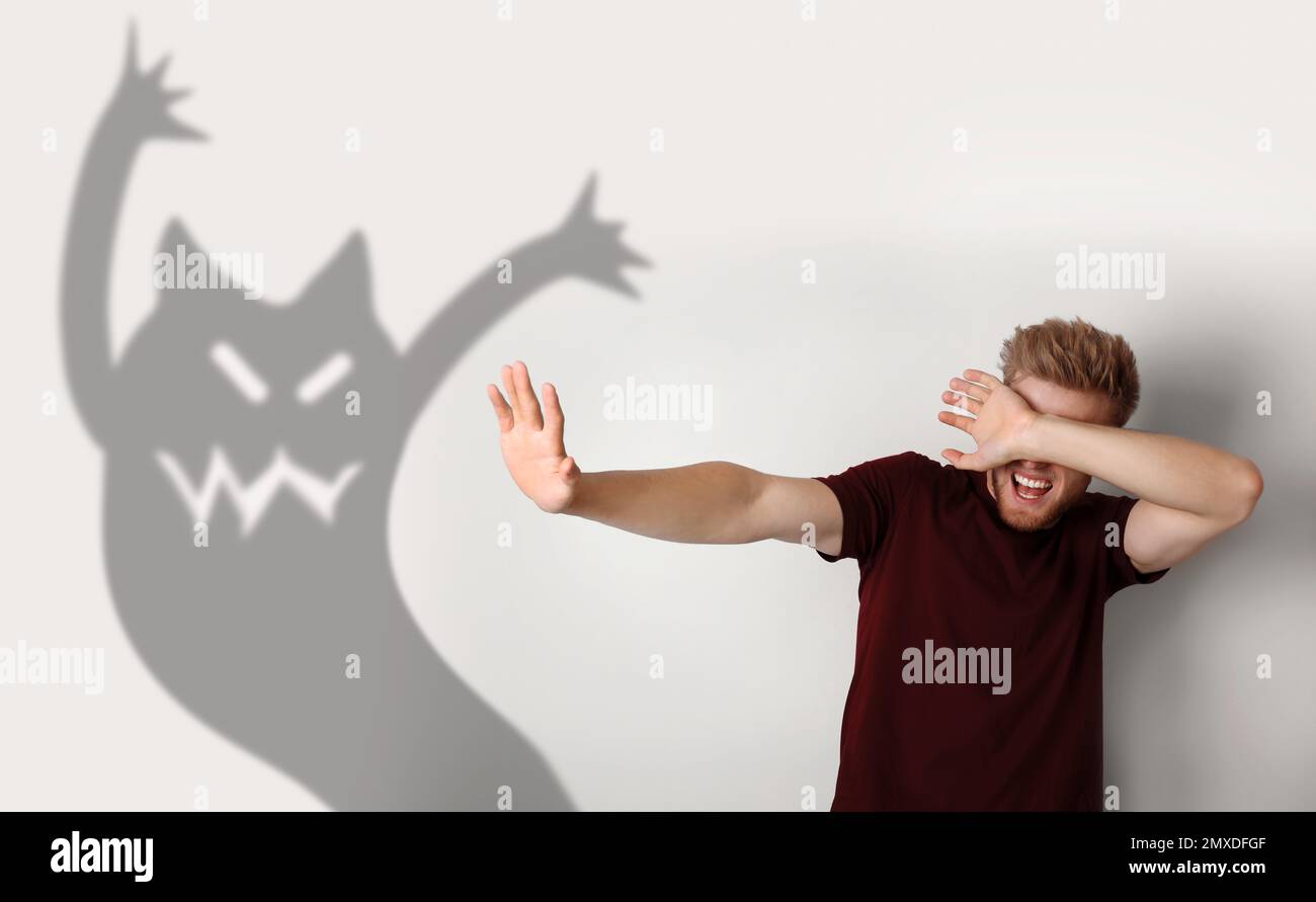 Scared young man suffering from sciophobia and phantom behind him ...