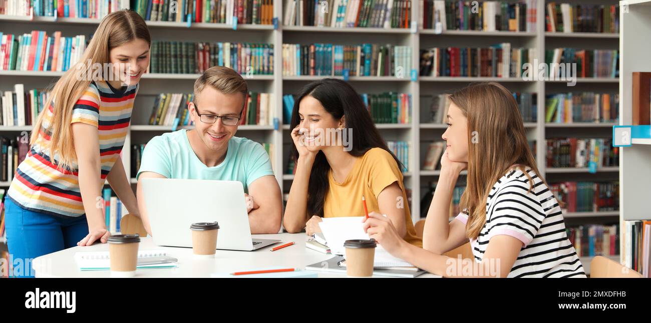 Young students discussing group project at table in library. Banner ...