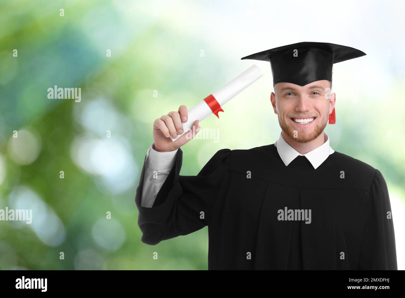 Happy student with graduation hat and diploma on blurred background ...