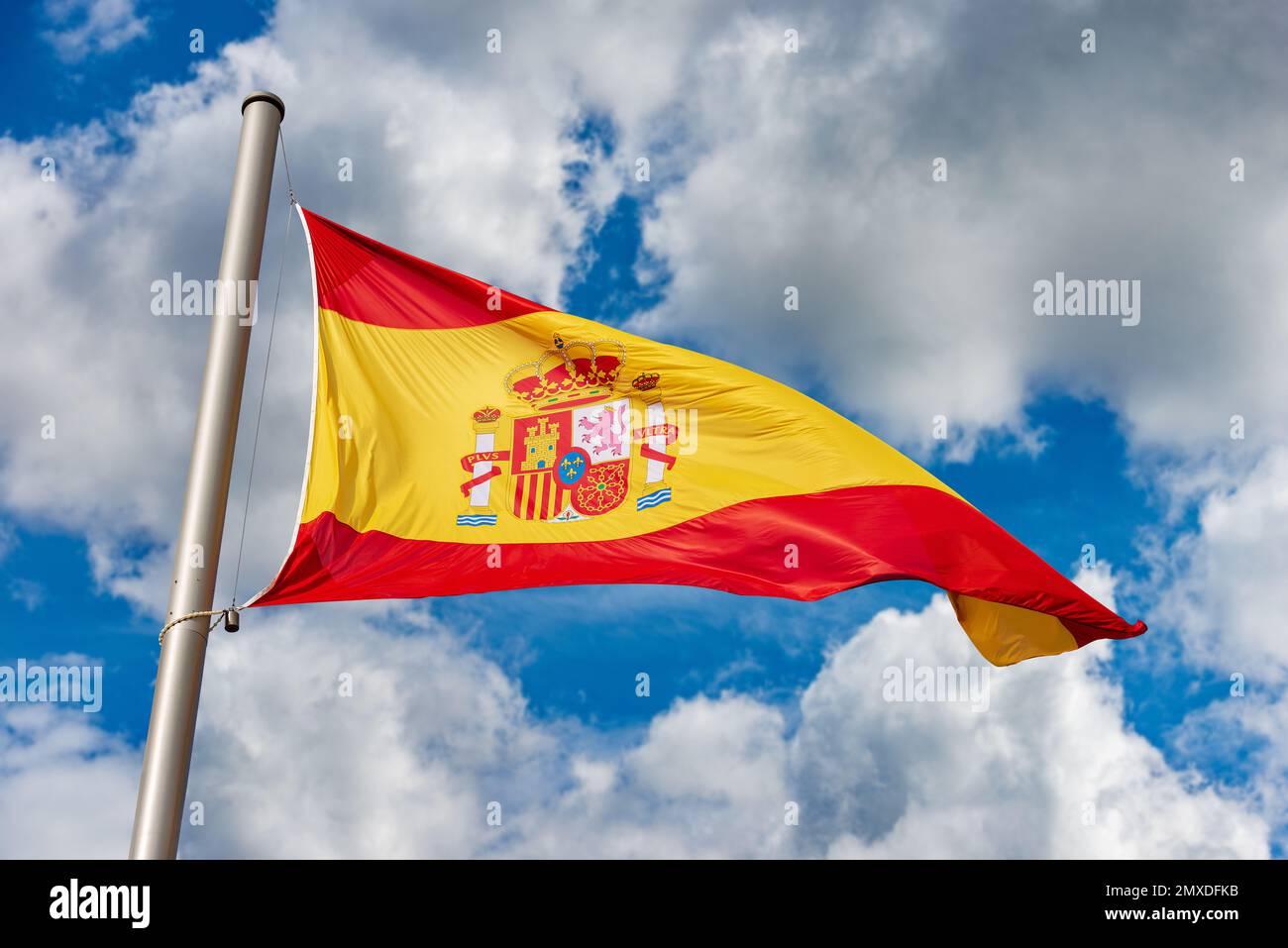 Closeup of a Spanish flag blowing in the wind against a blue sky with ...