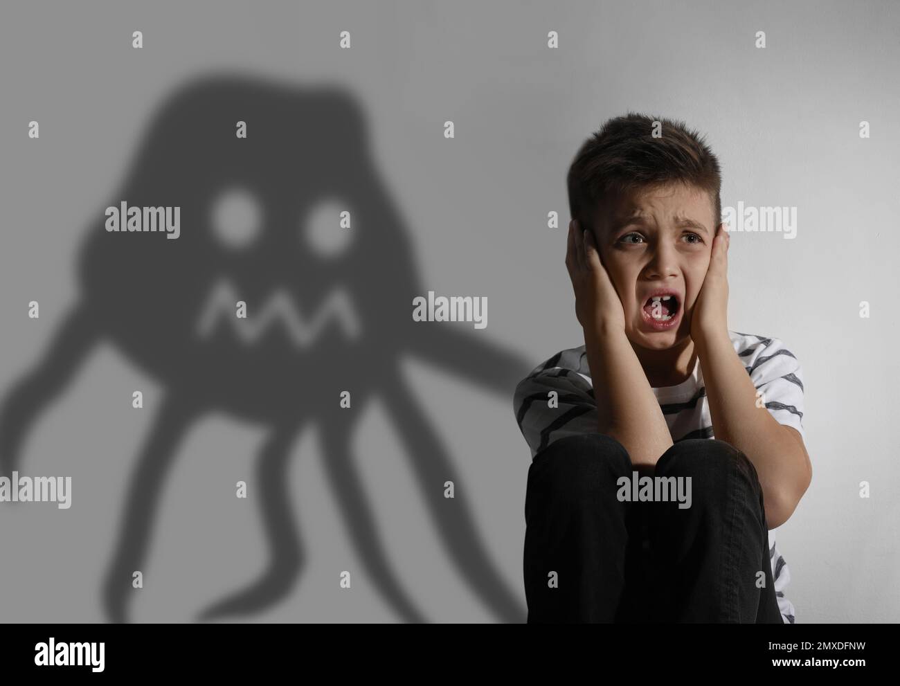 Scared little boy suffering from sciophobia and phantom behind him ...