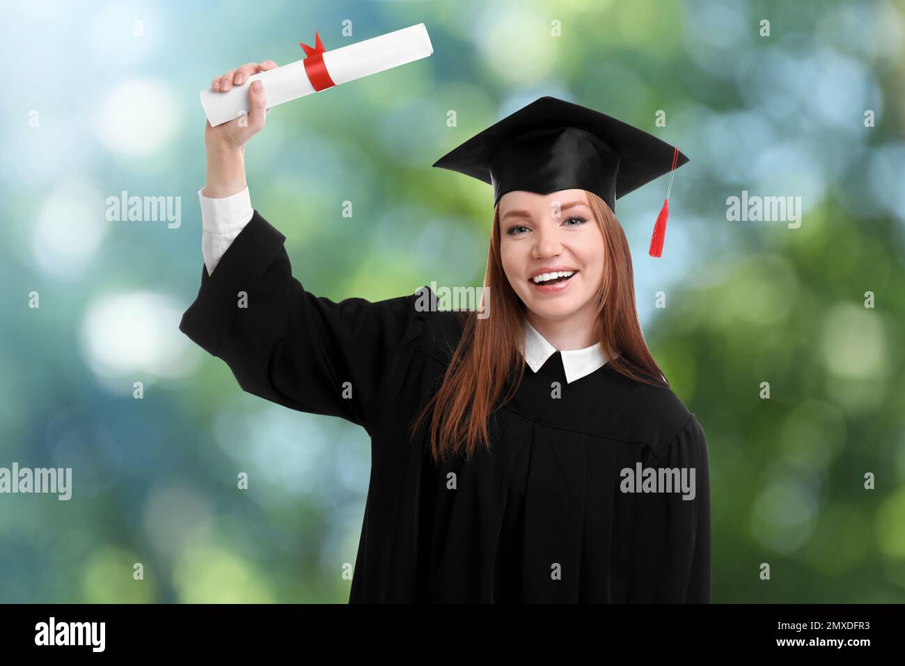 Happy student with graduation hat and diploma on blurred background ...