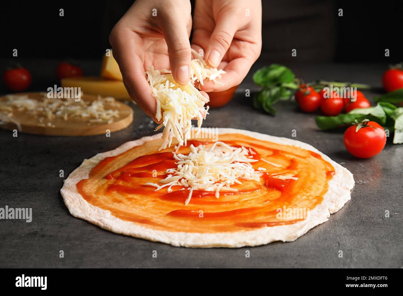 Woman adding cheese to pizza at grey table, closeup Stock Photo - Alamy
