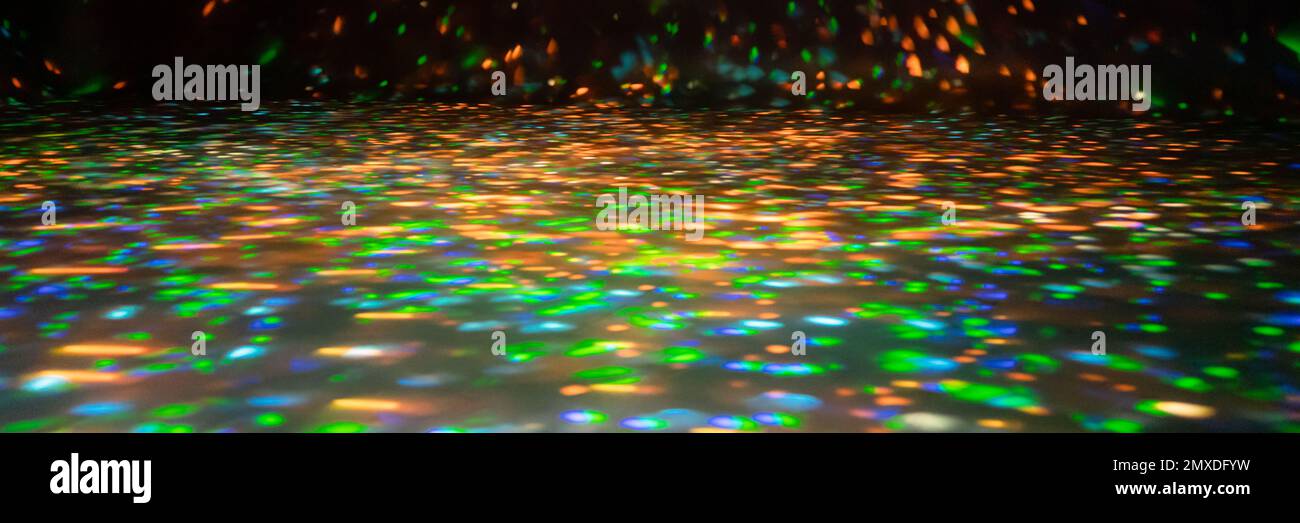 blurred rays of light on disco floor. orange green blue neon ...