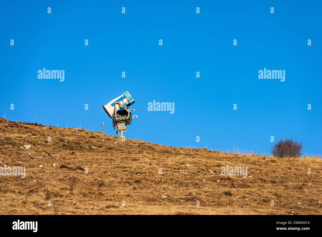 Snow cannon or snowmaking system in winter on a brown meadow, ski slope ...