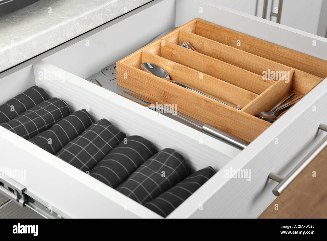 Open drawer with different utensils and folded towels. Order in kitchen ...