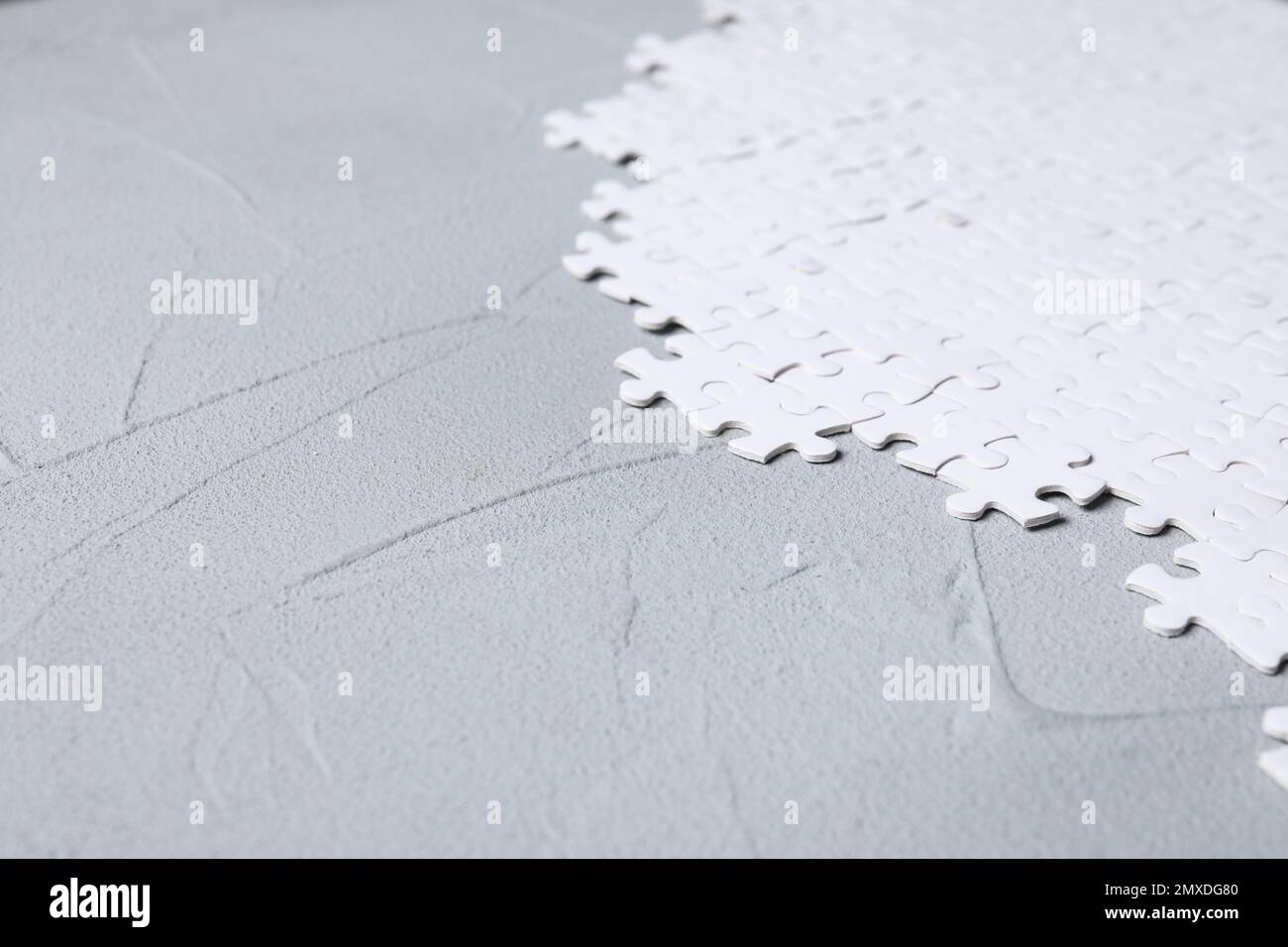 Blank white puzzle pieces on light grey stone background. Space for ...