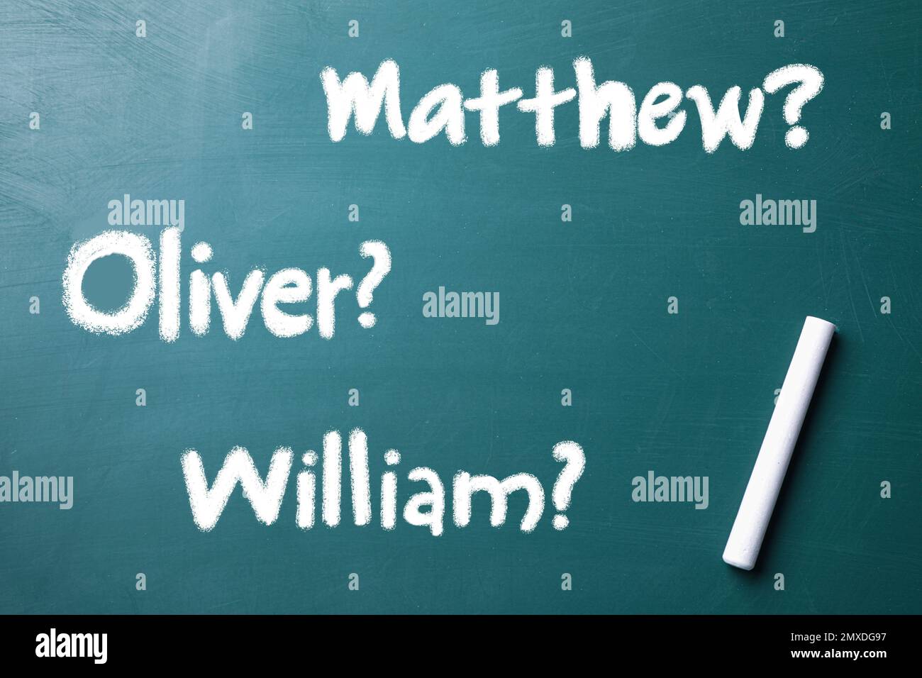 Piece of white chalk and different baby names written on greenboard ...