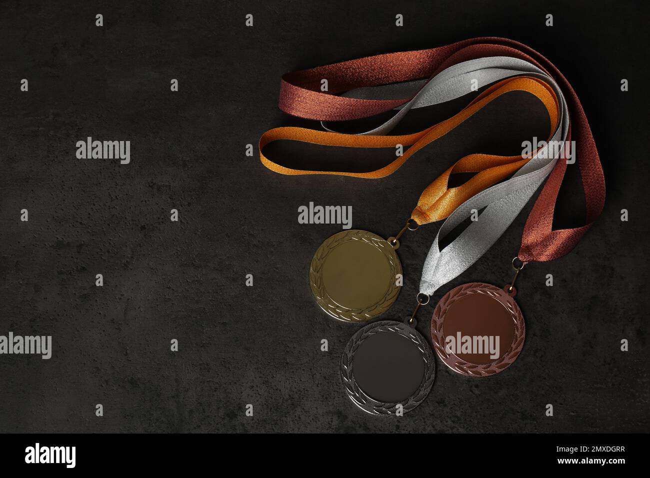 Gold, silver and bronze medals on grey stone background, flat lay ...