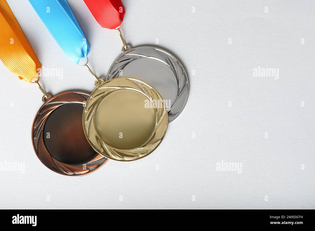 Gold, silver and bronze medals on white background, flat lay. Space for ...
