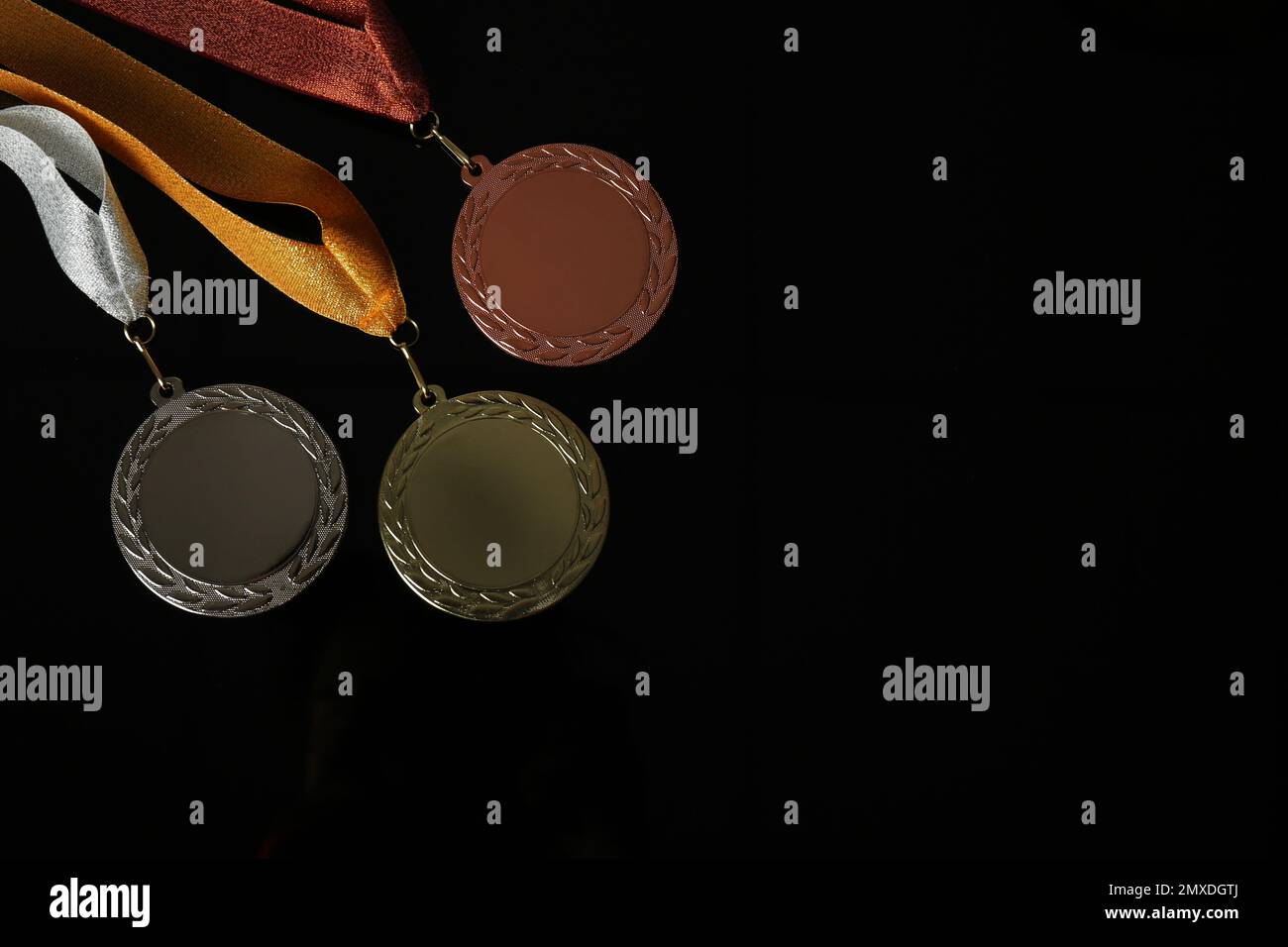Gold, silver and bronze medals on black background, flat lay. Space for ...