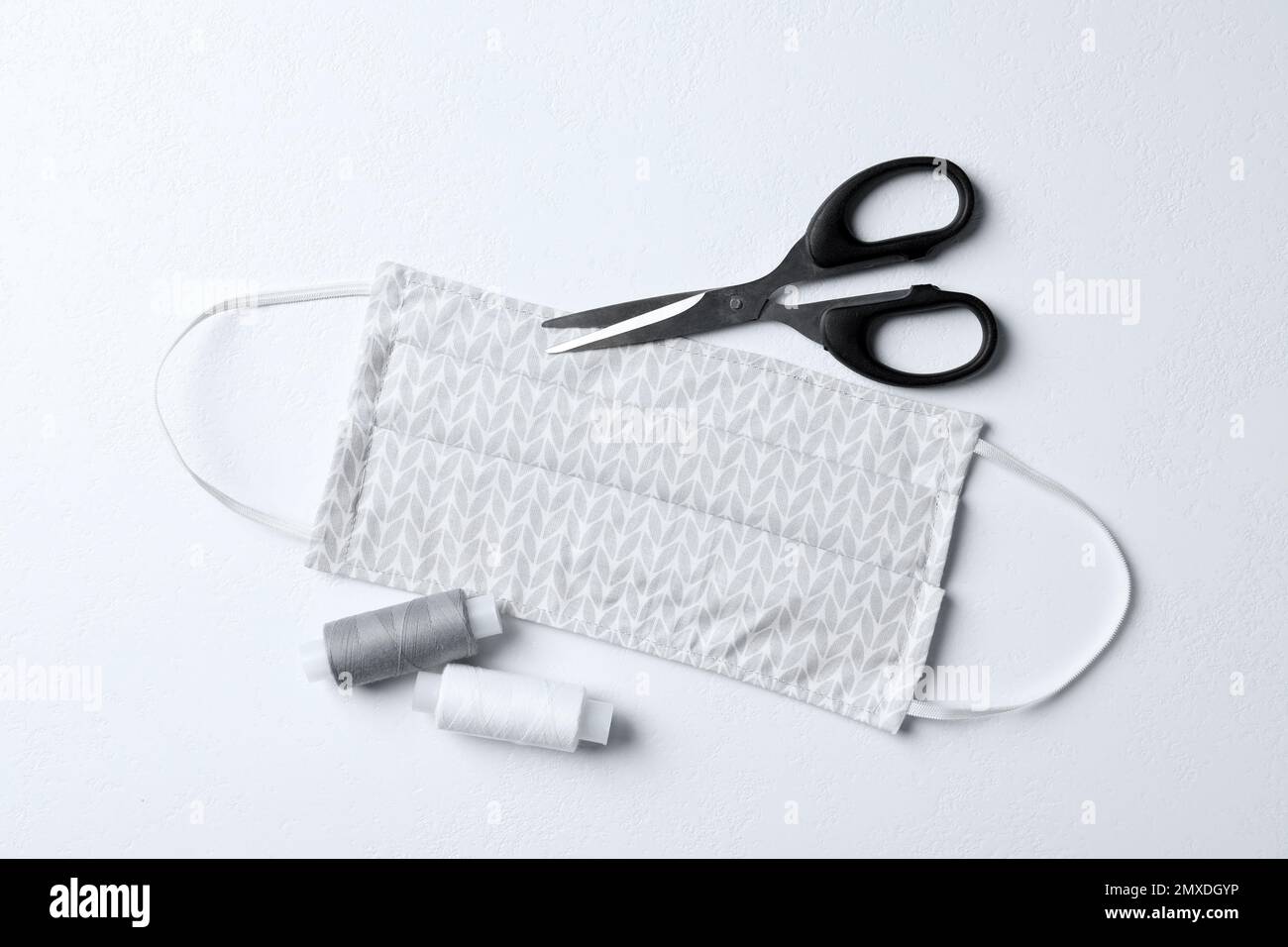 Homemade protective mask, threads and scissors on white background ...