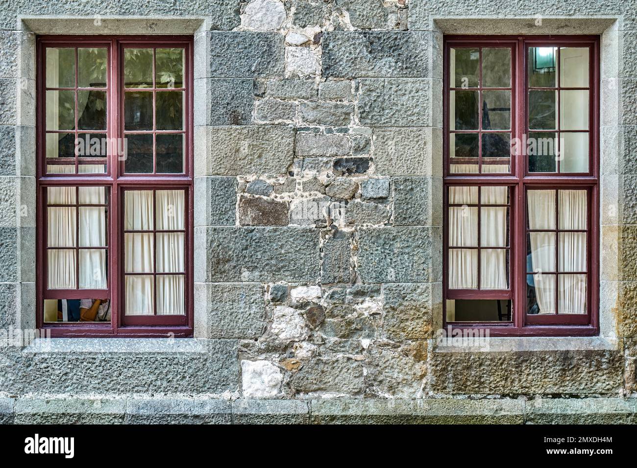 Old windows with white curtains on stone wall of historical building ...