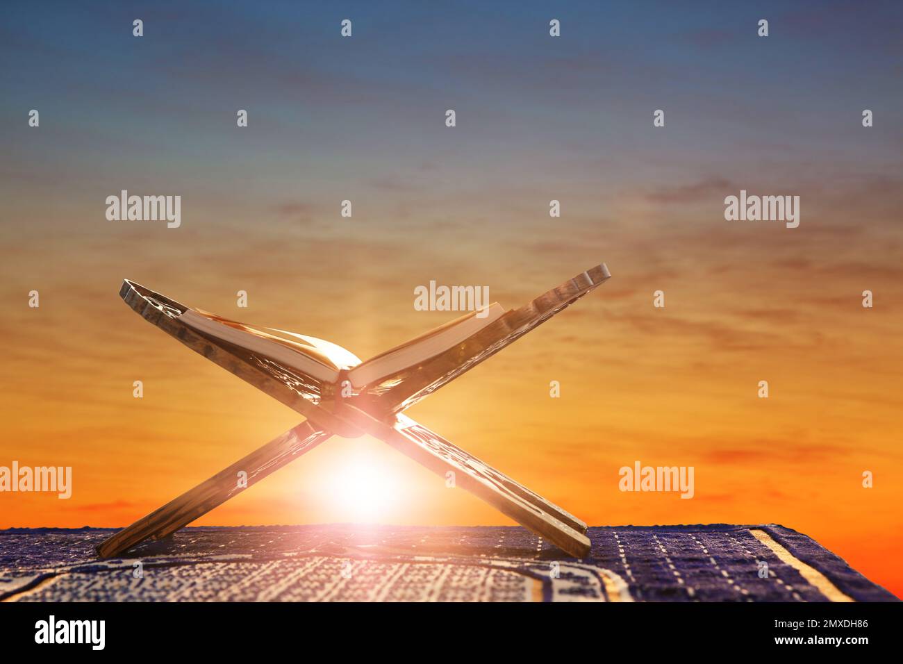 Rehal with open Quran on Muslim prayer rug at sunset. Holy month of ...