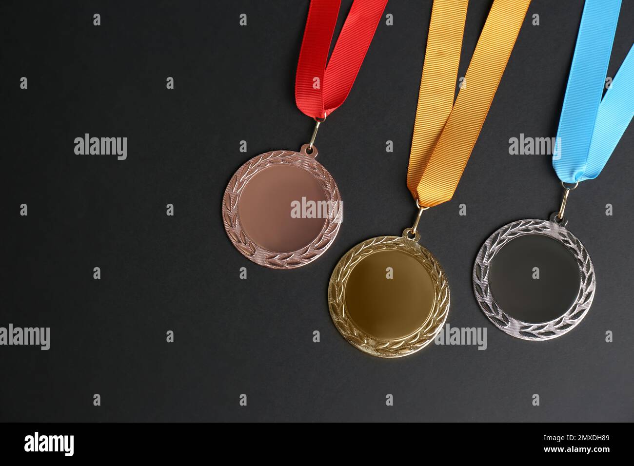 Gold, silver and bronze medals on black background, flat lay. Space for ...