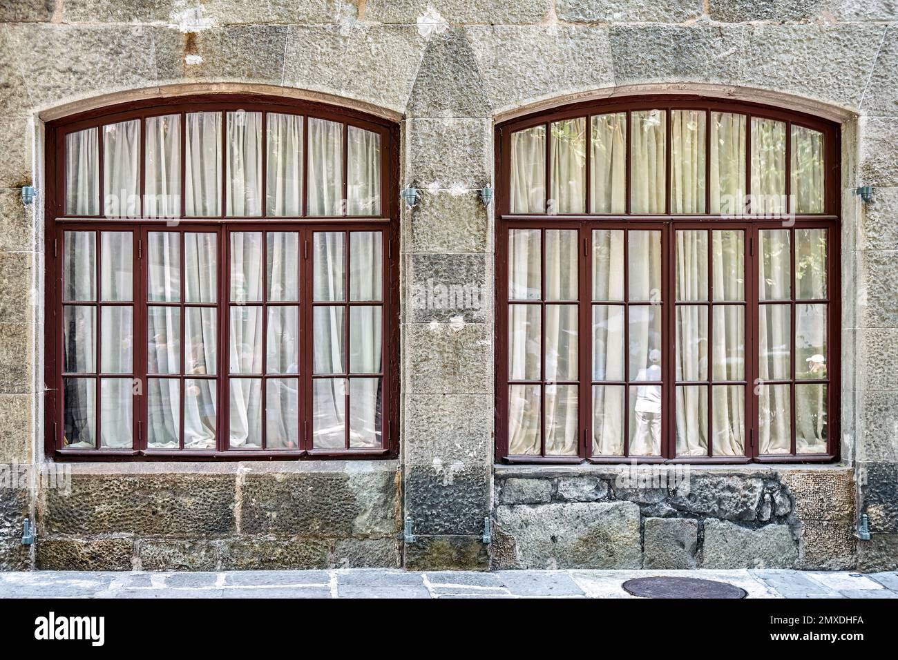 Old arched windows with white curtains on stone wall of historical ...