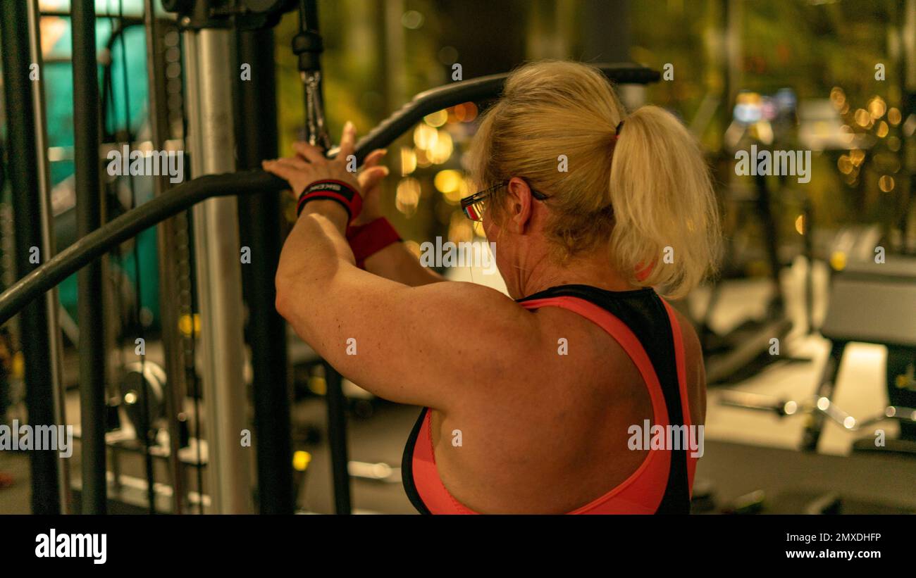 A fit blonde female with toned muscles working out arms at the gym ...
