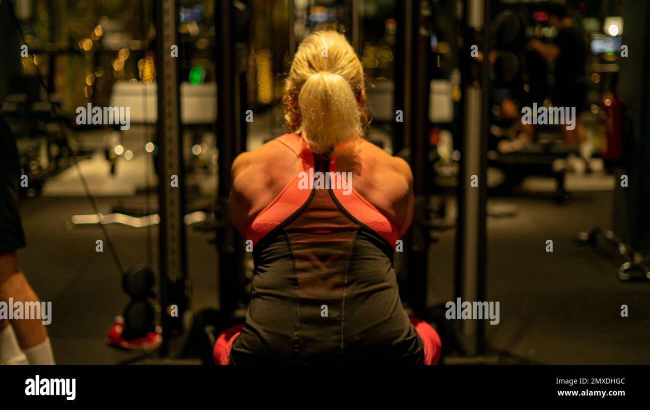 A fit blonde female with toned muscles working out arms at the gym ...