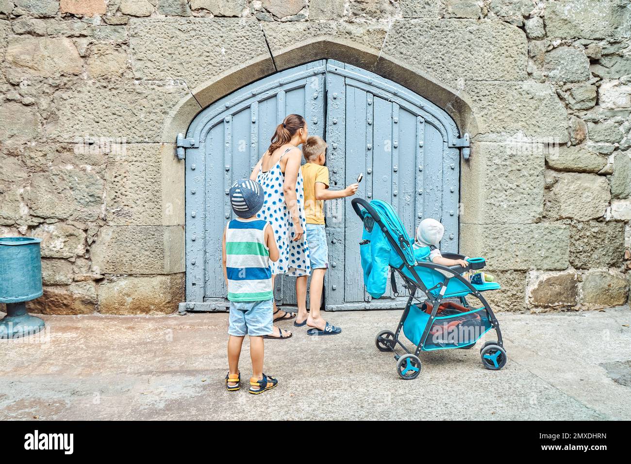 Family members walk together and try to look through wooden gate in ...