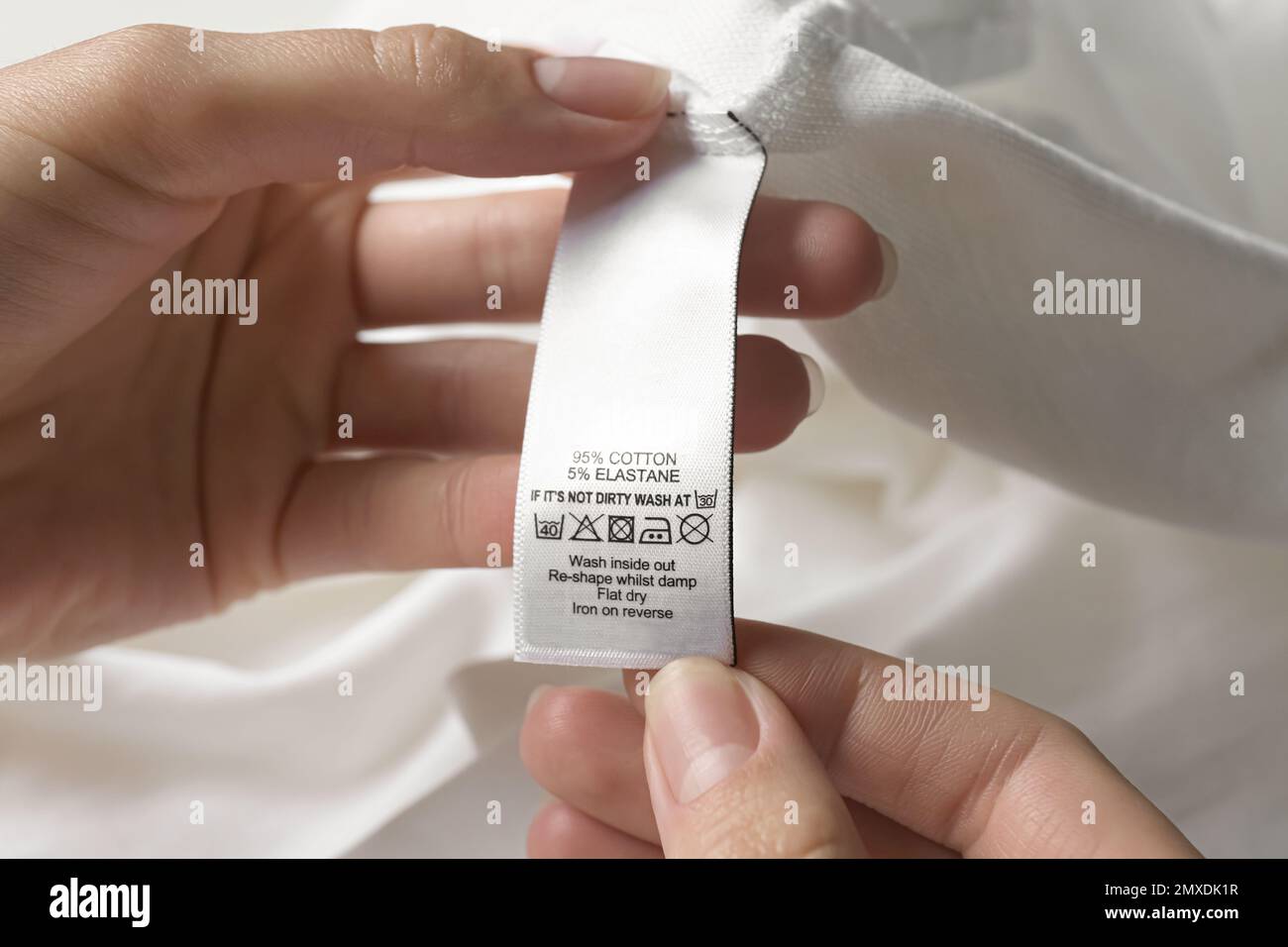 Woman reading clothing label with care symbols and material content on ...