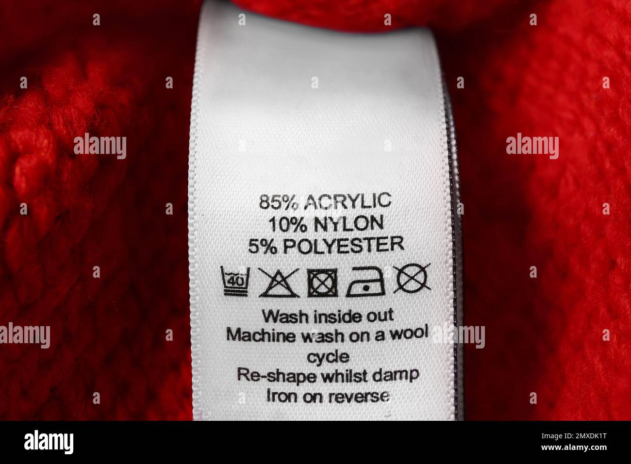 Clothing label with care symbols and material content on red sweater ...