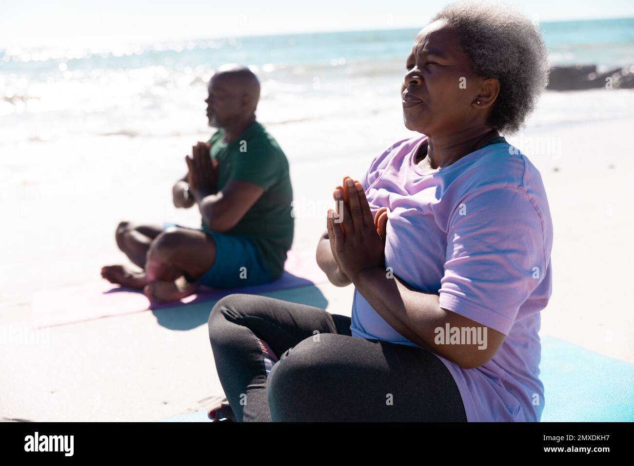 African american senior couple in prayer pose meditating while sitting ...