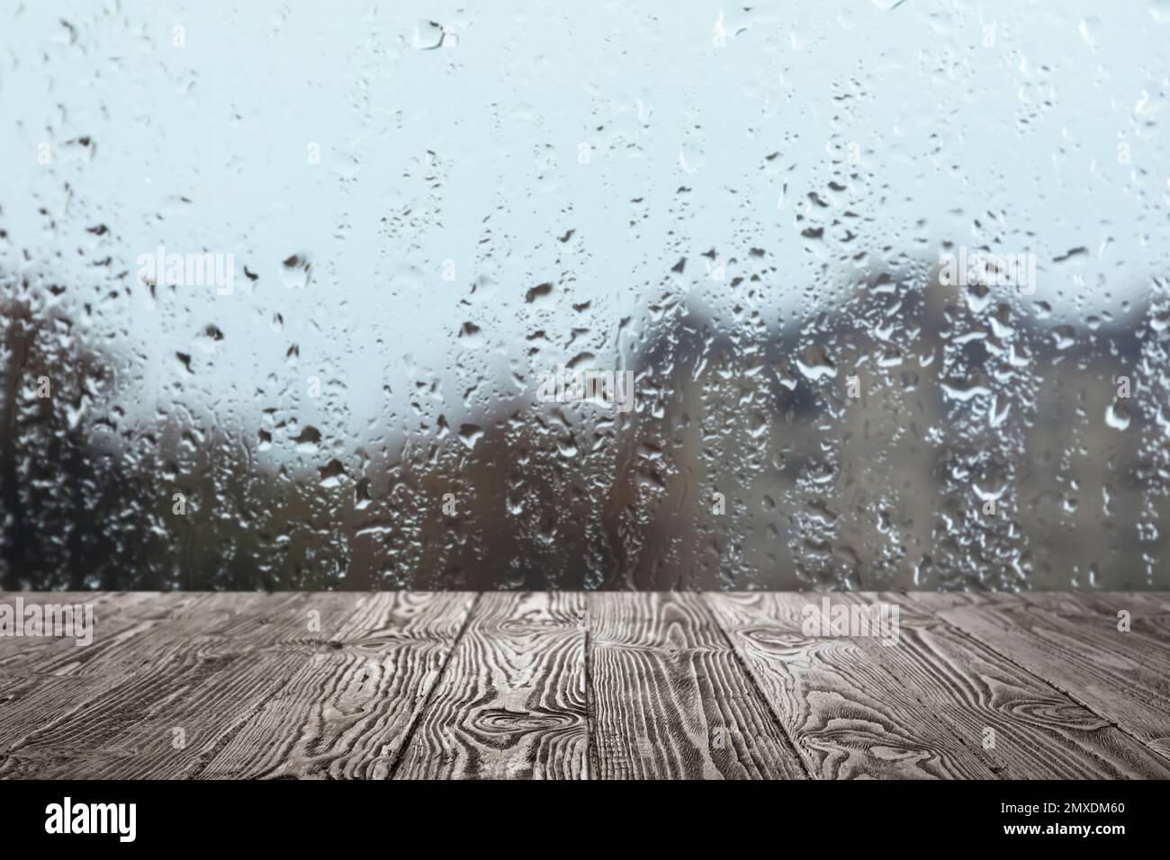 Wooden table near window on rainy day Stock Photo - Alamy