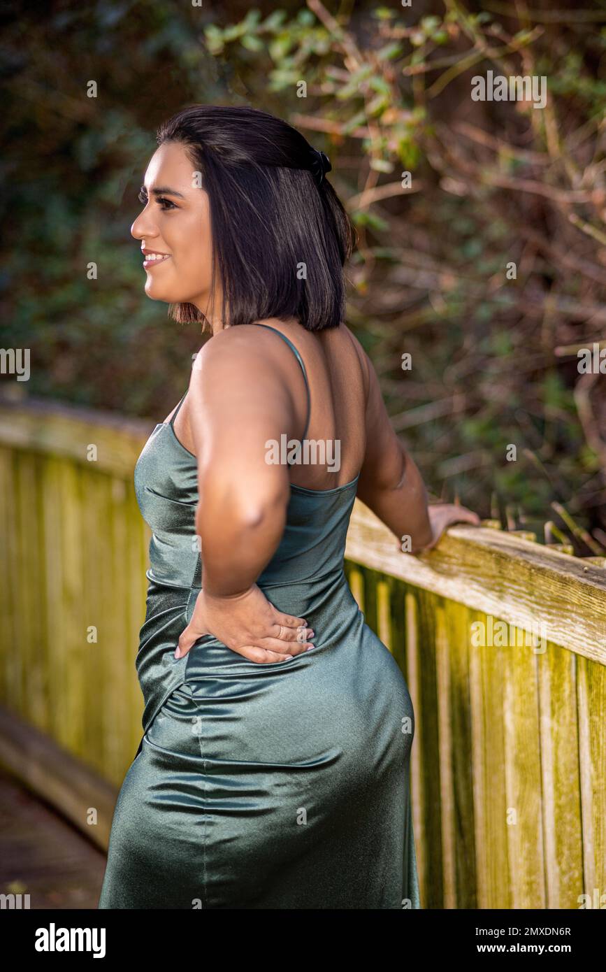 A beautiful Hispanic model posing in a green dress outdoors during ...