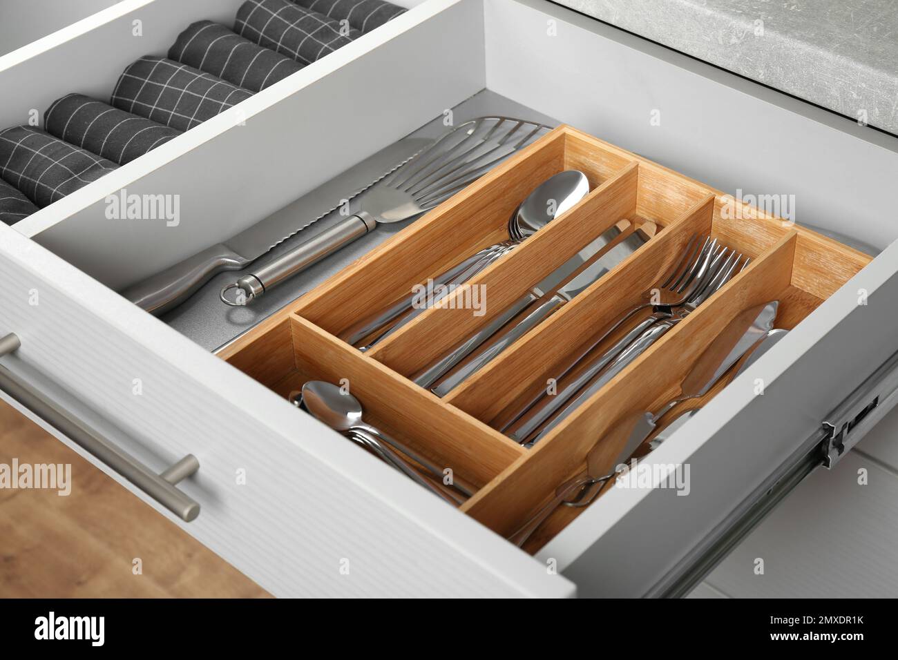 Open drawer with different utensils and folded towels. Order in kitchen ...