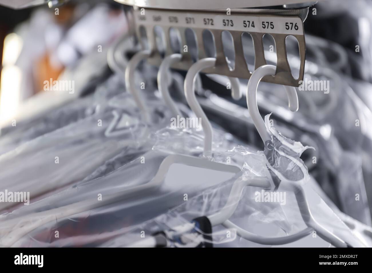 Hangers with clothes on garment conveyor at dry-cleaner's, closeup ...