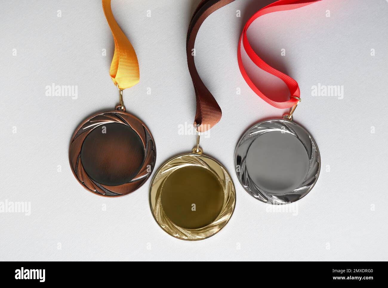 Gold, silver and bronze medals on white background, flat lay. Space for ...