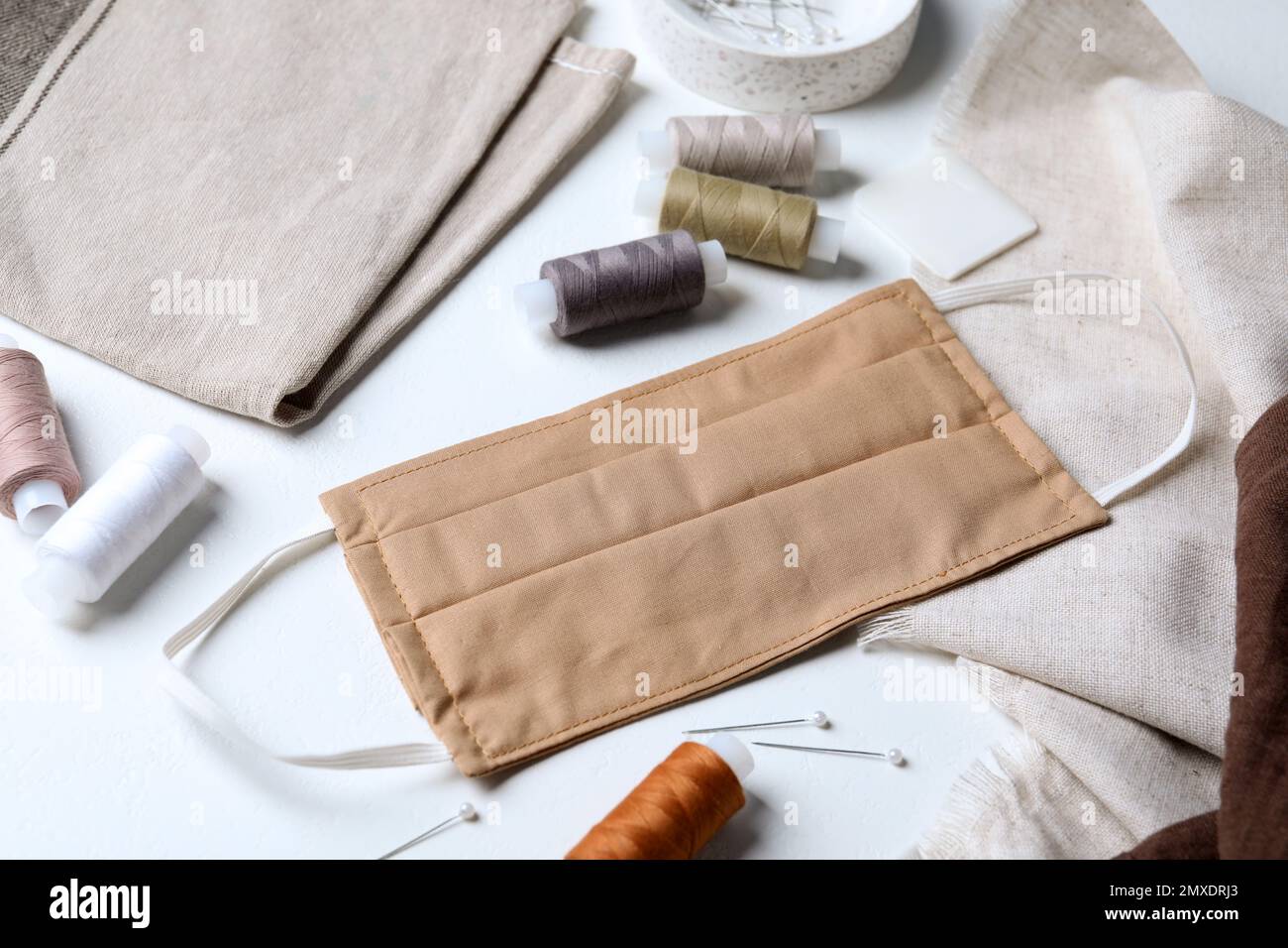 Homemade protective mask and sewing accessories on white background ...